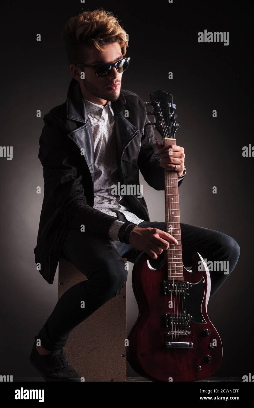 side view of a rock and roll guitarist holding his electric guitar and ...