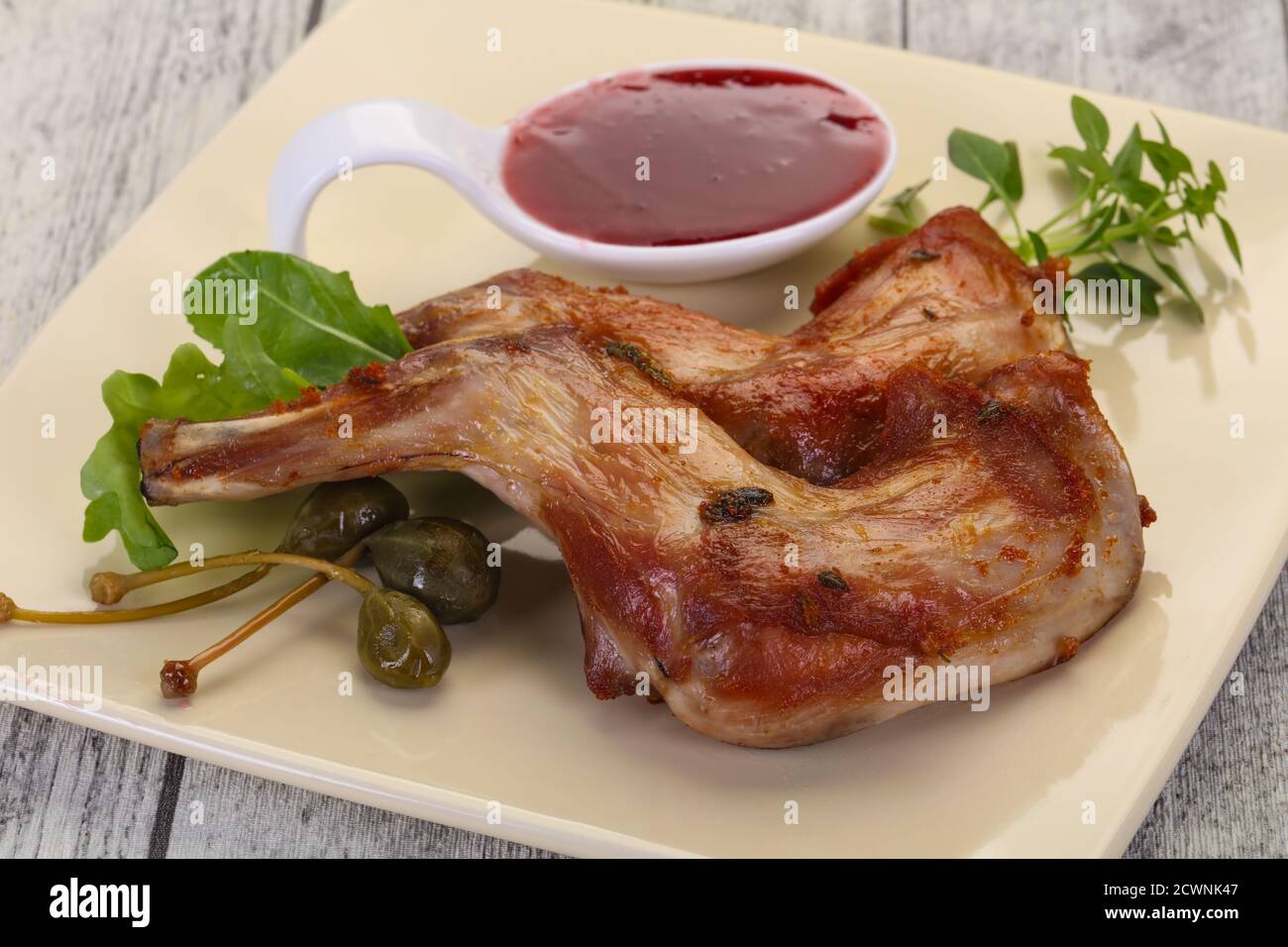 Roasted rabbit legs with cowberry sauce Stock Photo - Alamy
