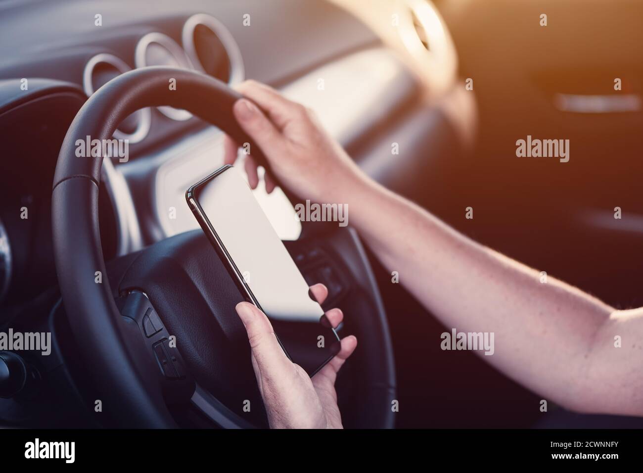 Woman texting on mobile phone in the car while holding steering wheel ...