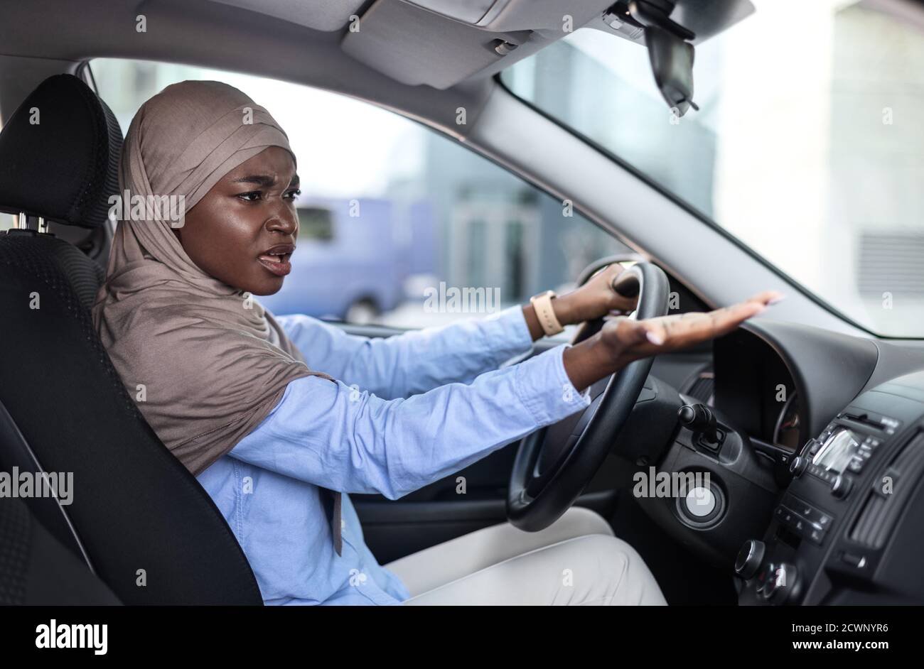 Stressed black muslim woman arguing with someone while driving car ...