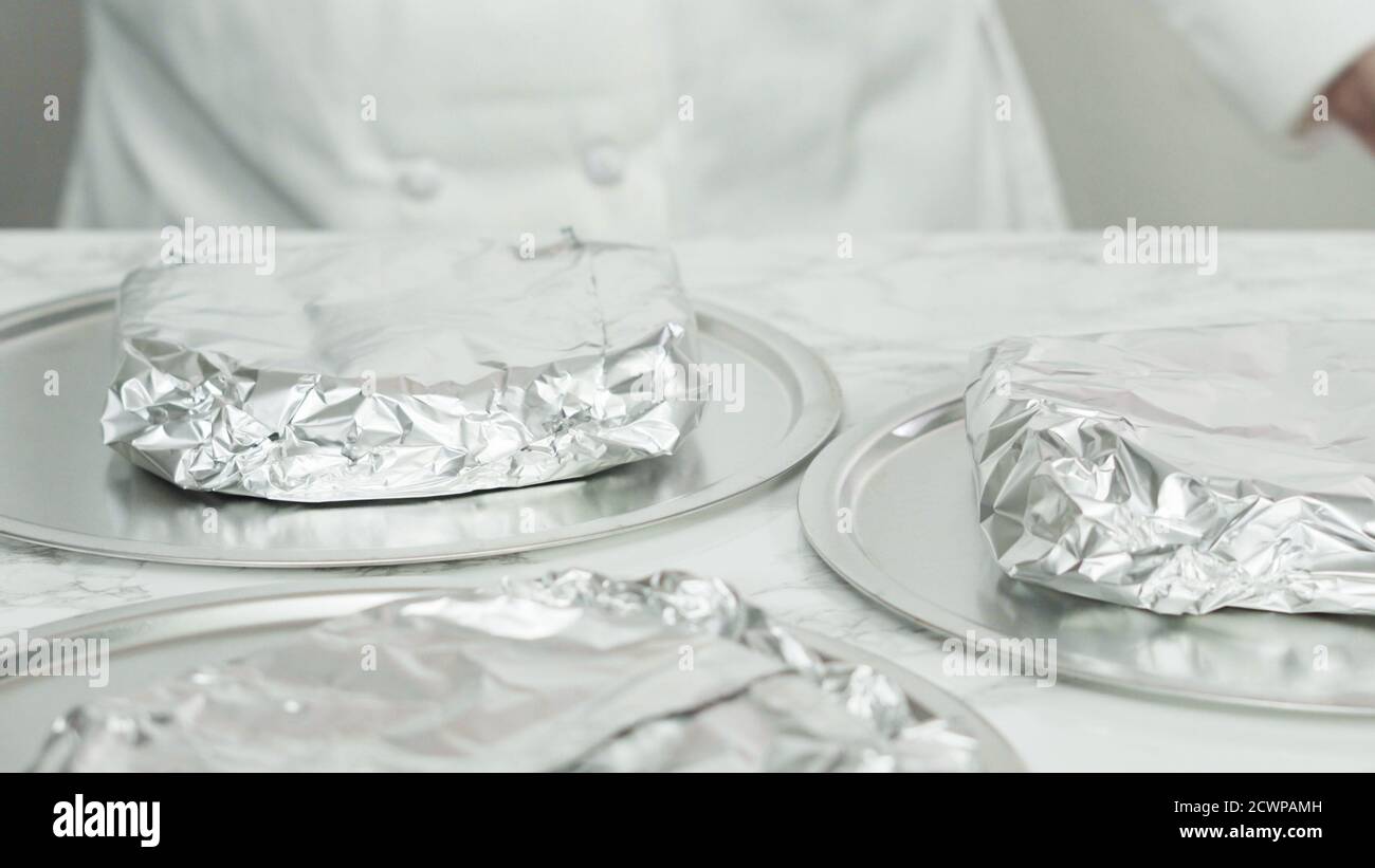 Step by step. Wrapping freshly baked cake layers into clear food wrap ...