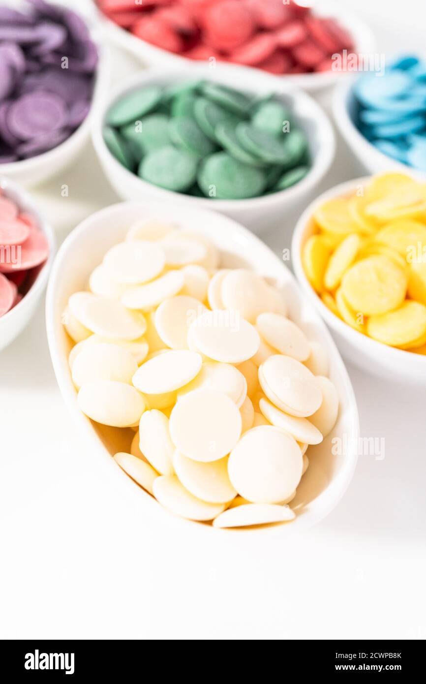 Rainbow colors of round chocolate chips in a white bowls for melting ...