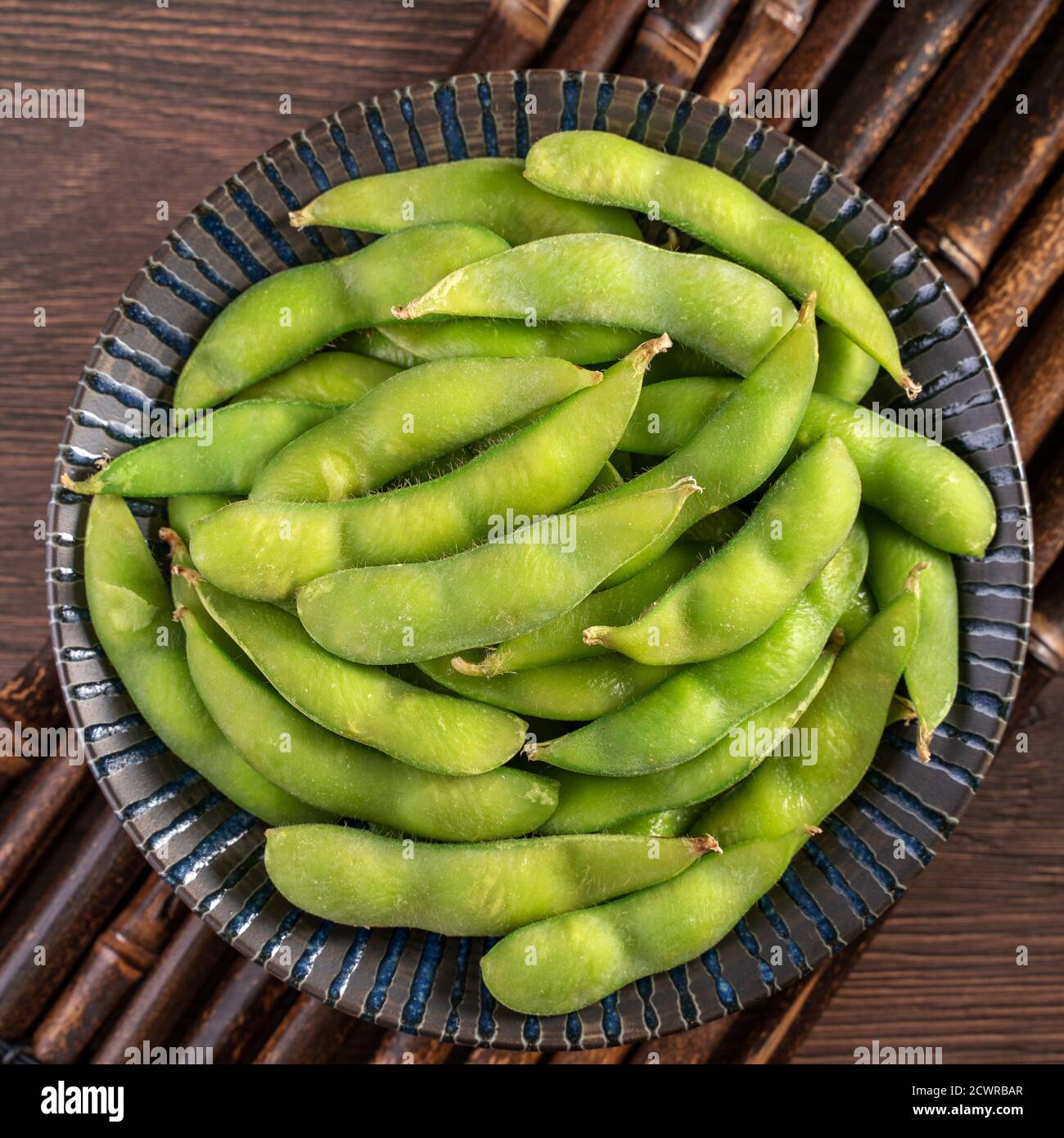 Fresh cooked boiled edamame in a plate on wooden tray and table ...