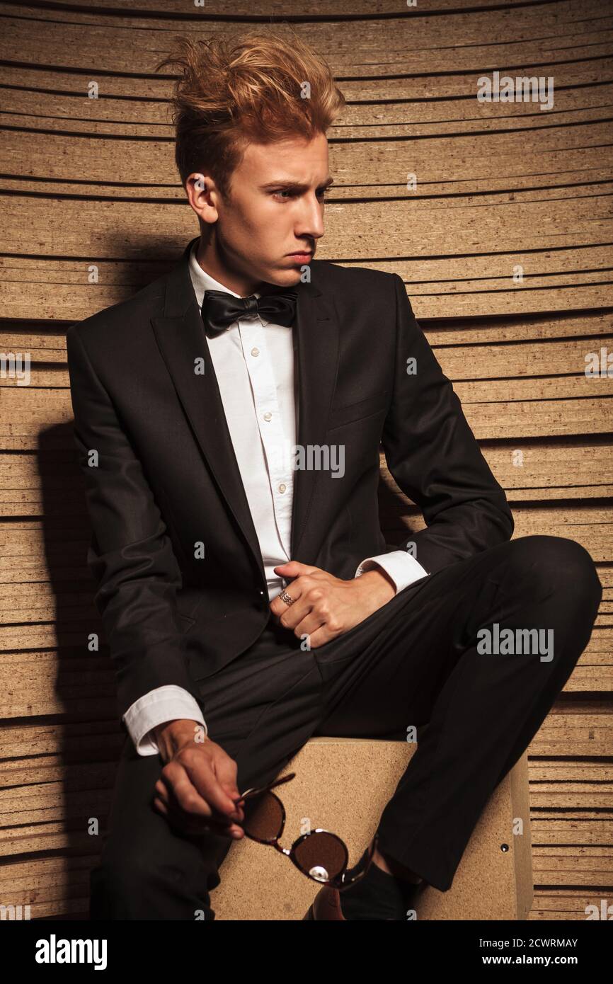 Side view of a young business man looking down while sitting on a chair ...