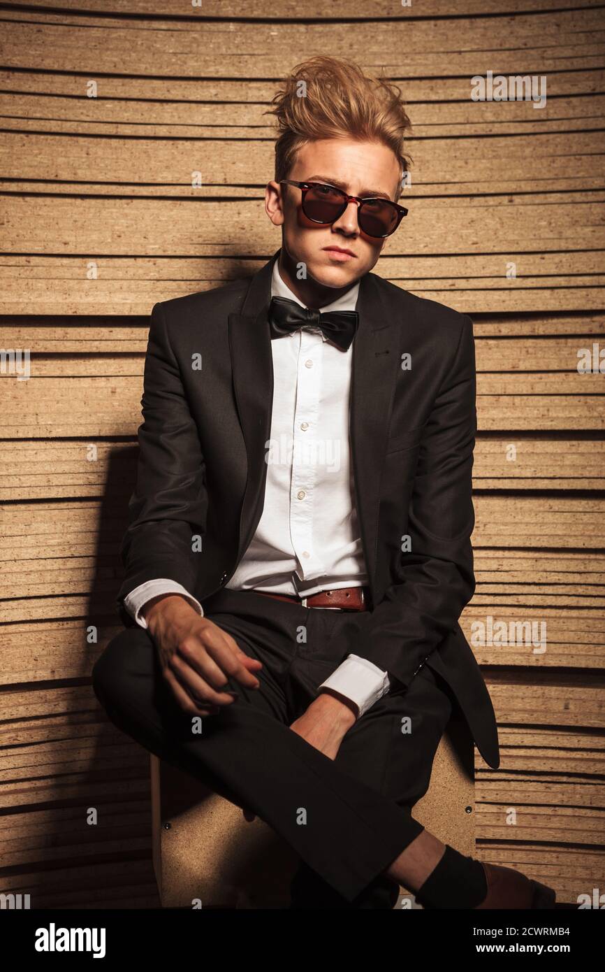 Young business man sitting with his legs crossed, looking at the camera ...