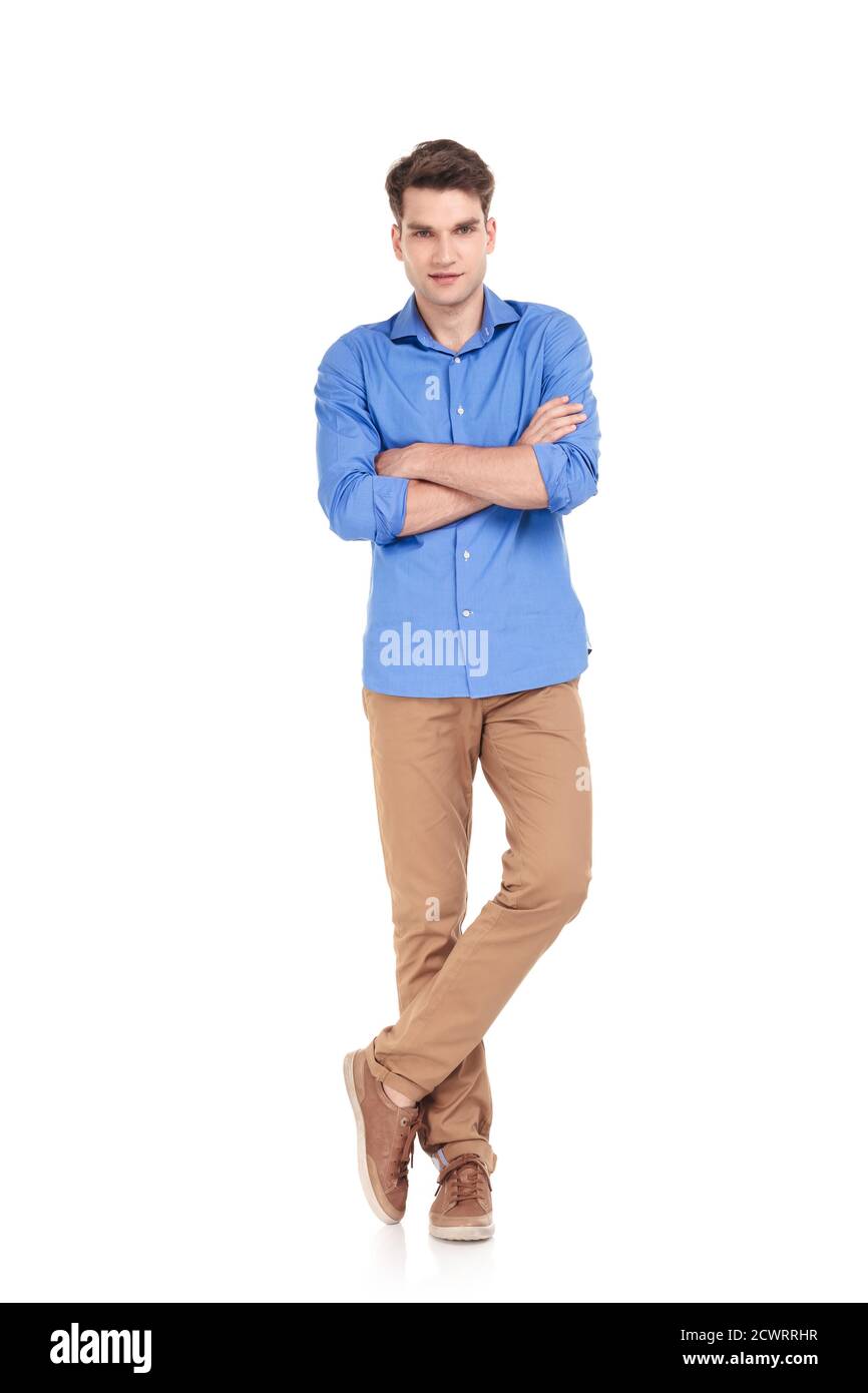 Handsome young man standing with his hands and legs crossed on isolated ...