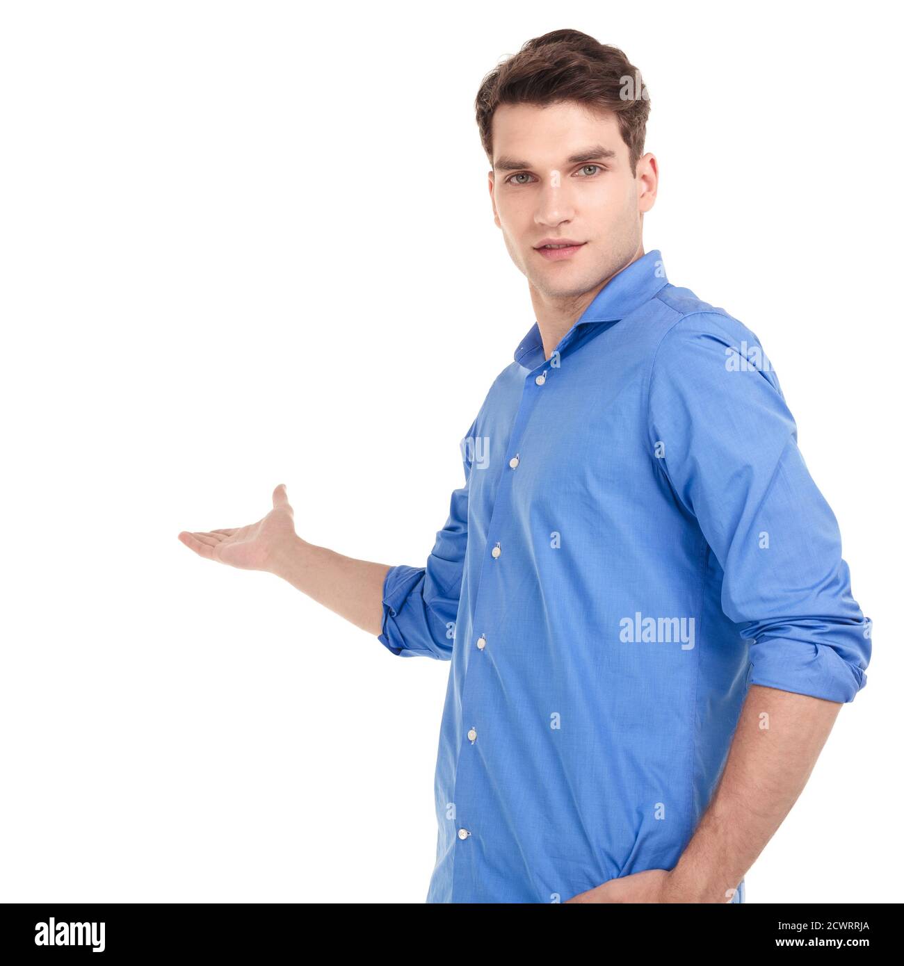 Young casual man presenting something on his right, looking at the ...
