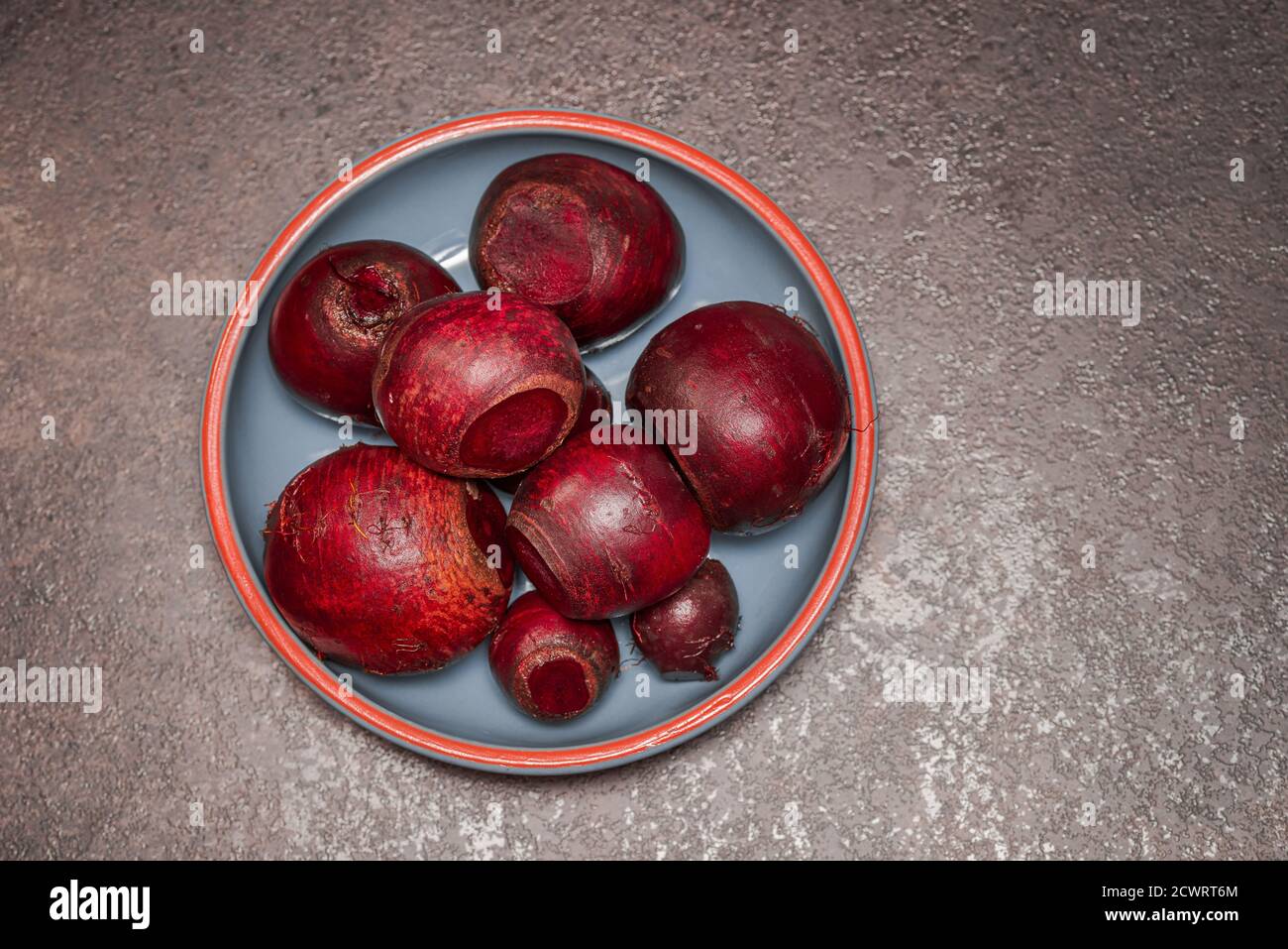 Pile of unpeeled bulbs of beetroot in different sizes on round plate ...