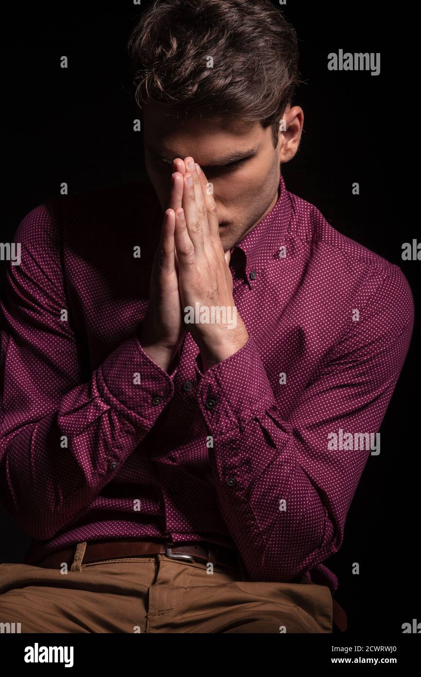 Young casual man sitting while holding his hands together Stock Photo ...