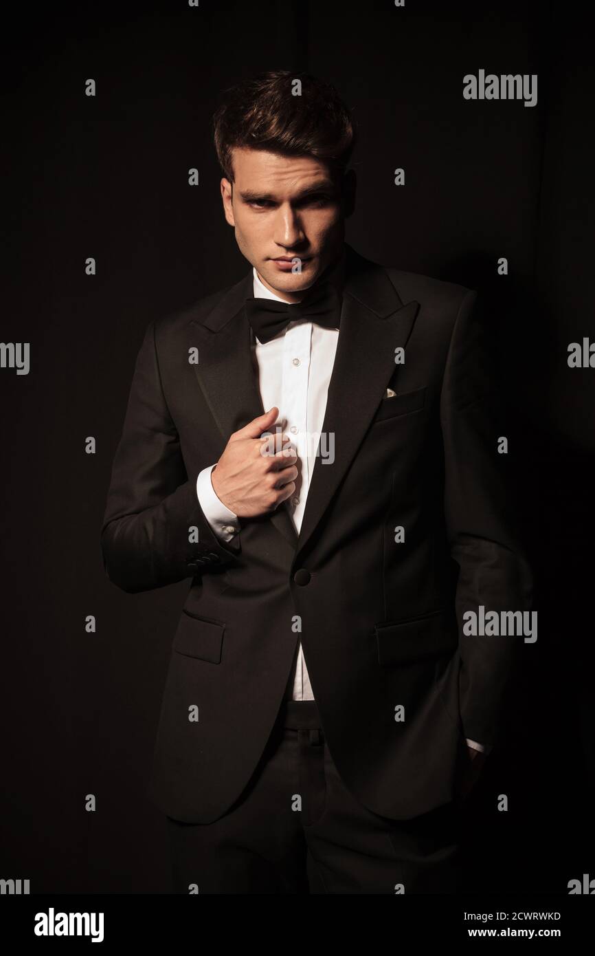 Attractive young business man looking at the camera while fixing his ...