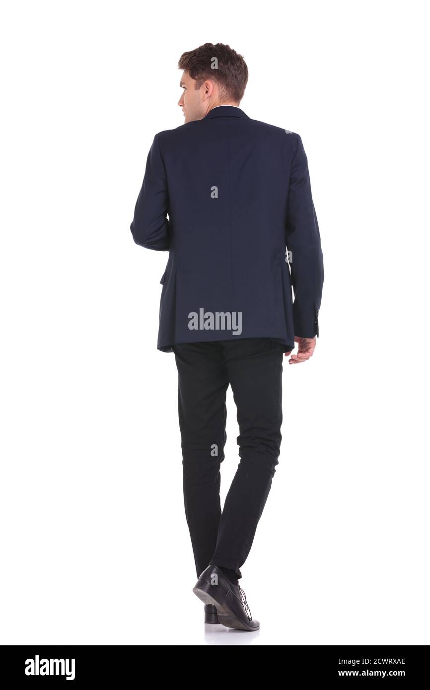 Back view of a young business man walking while looking to his side ...