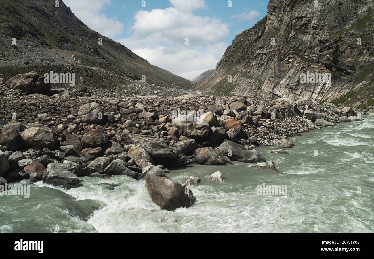 River flows through deep valley flanked by Himalayas and boulders under ...