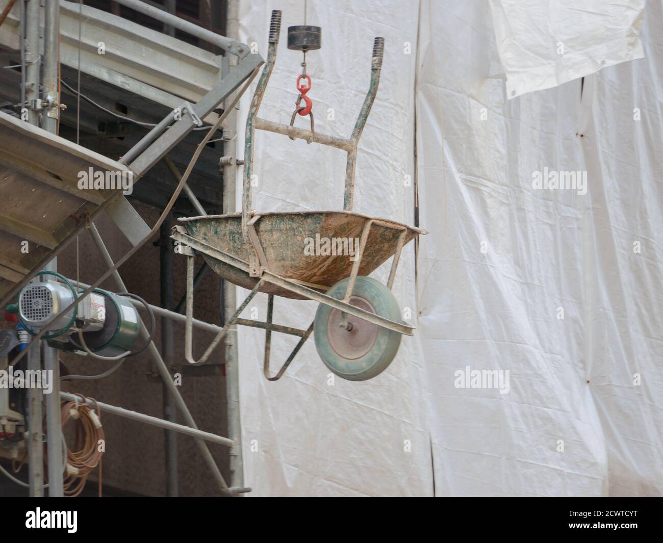 wheelbarrow is lifted on a construction site with a pulley during the ...