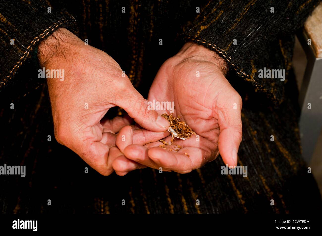 man with dark green chilaba, puts cigarette mouth in hand, prepares ...