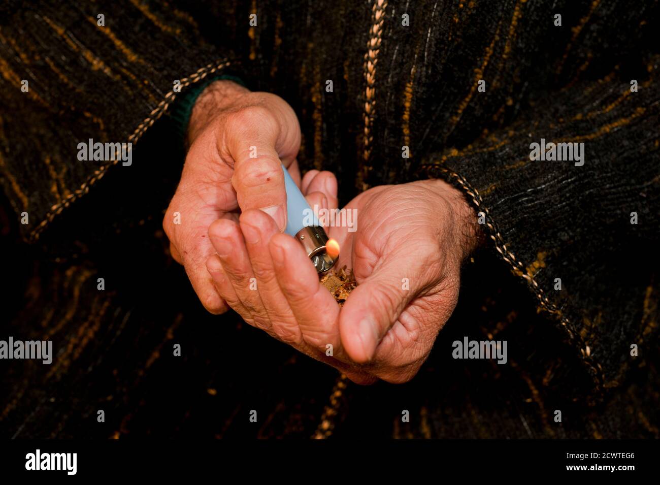 man hands with dark squeaky fire lighter lit cigar in hand warming ...