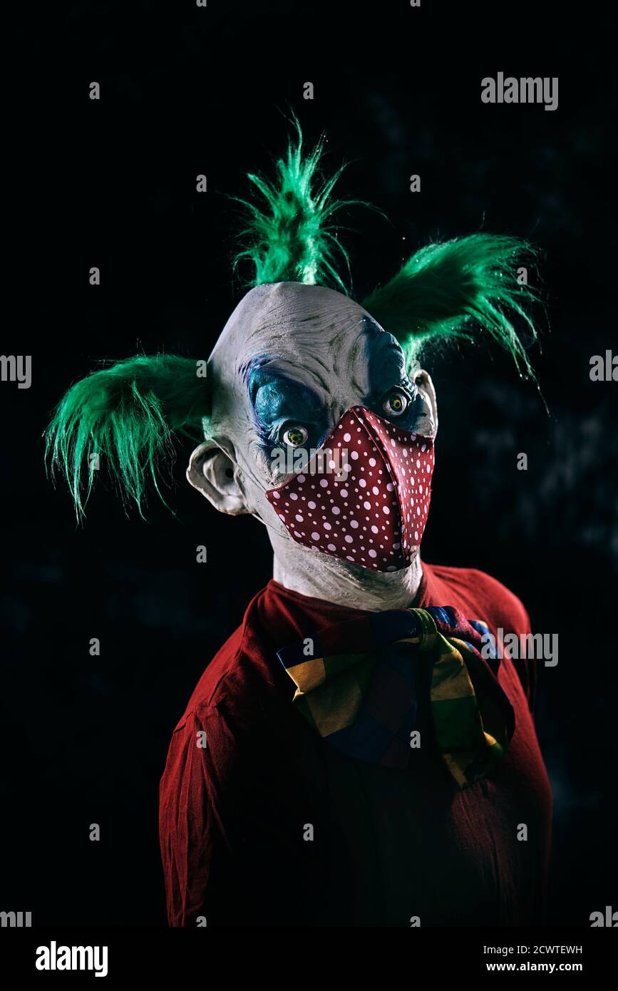 closeup of a disturbing evil clown, with green hair, wearing a dirty ...