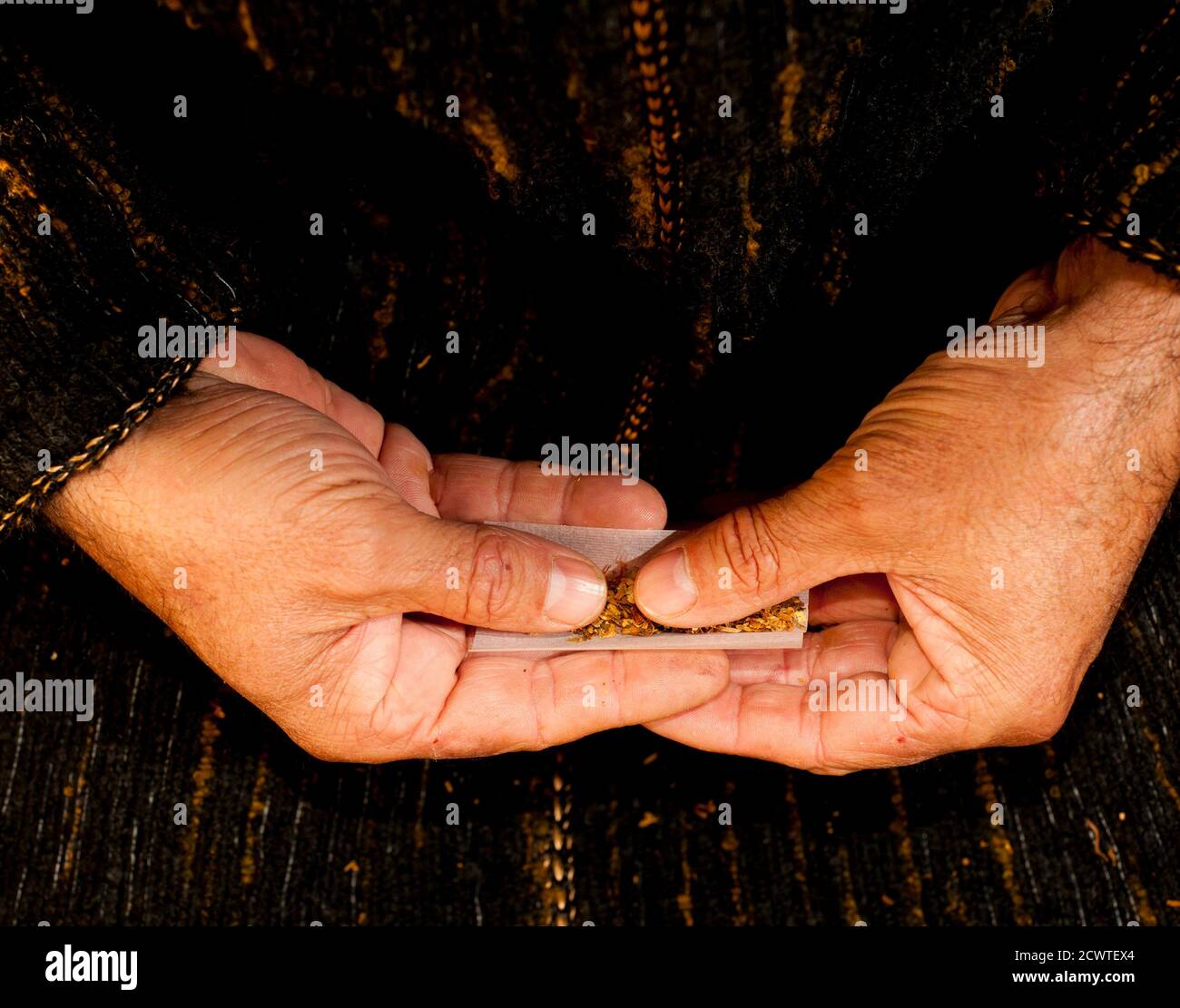 man with dark green chilaba, puts cigarette mouth in hand, prepares ...