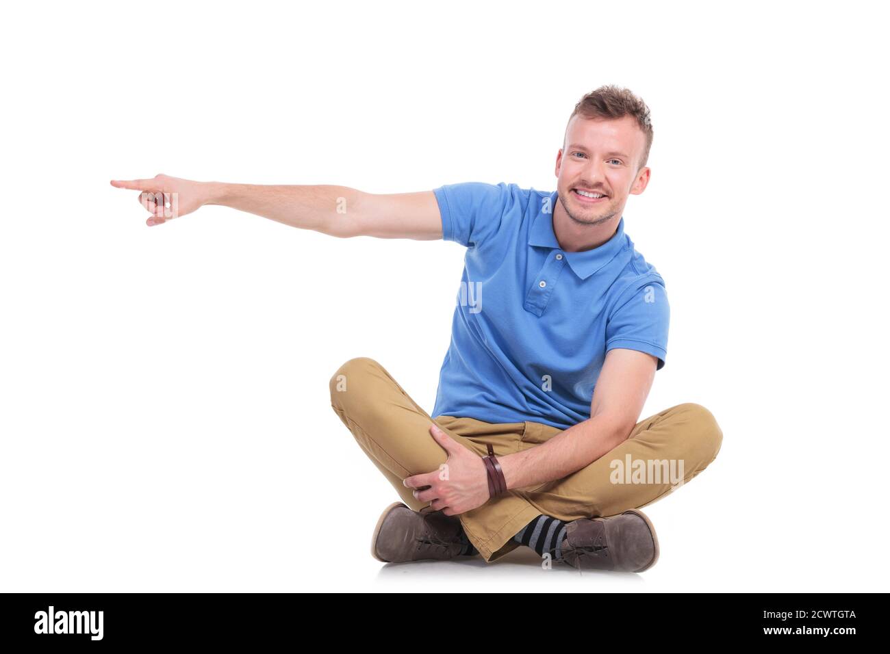 casual young man sitting on the floor with his legs crossed and ...