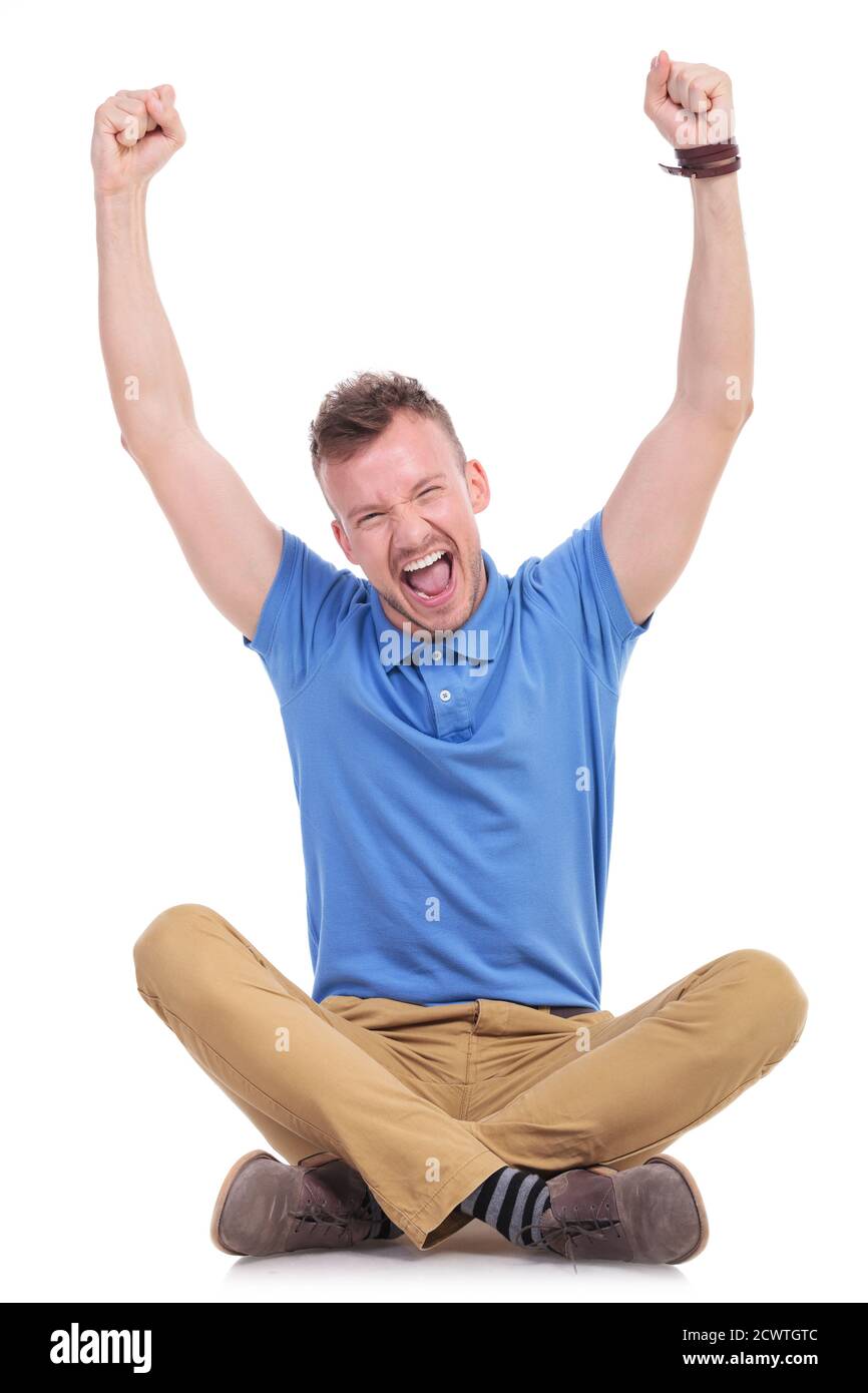 casual young man sitting on the floor with his legs crossed and ...