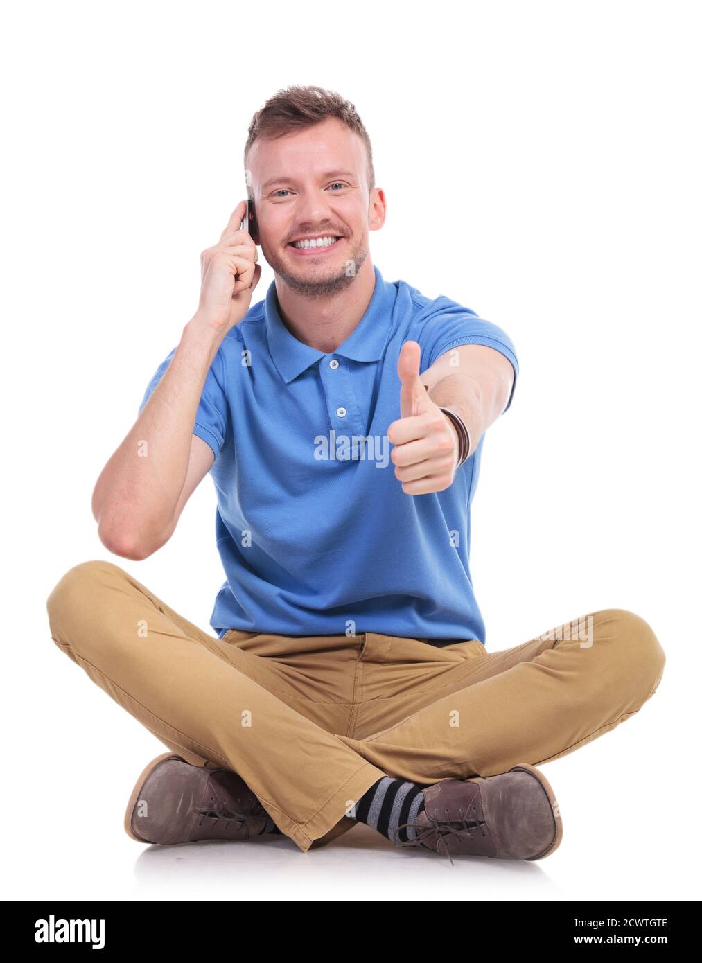 casual young man sitting on the floor with his legs crossed and talking ...