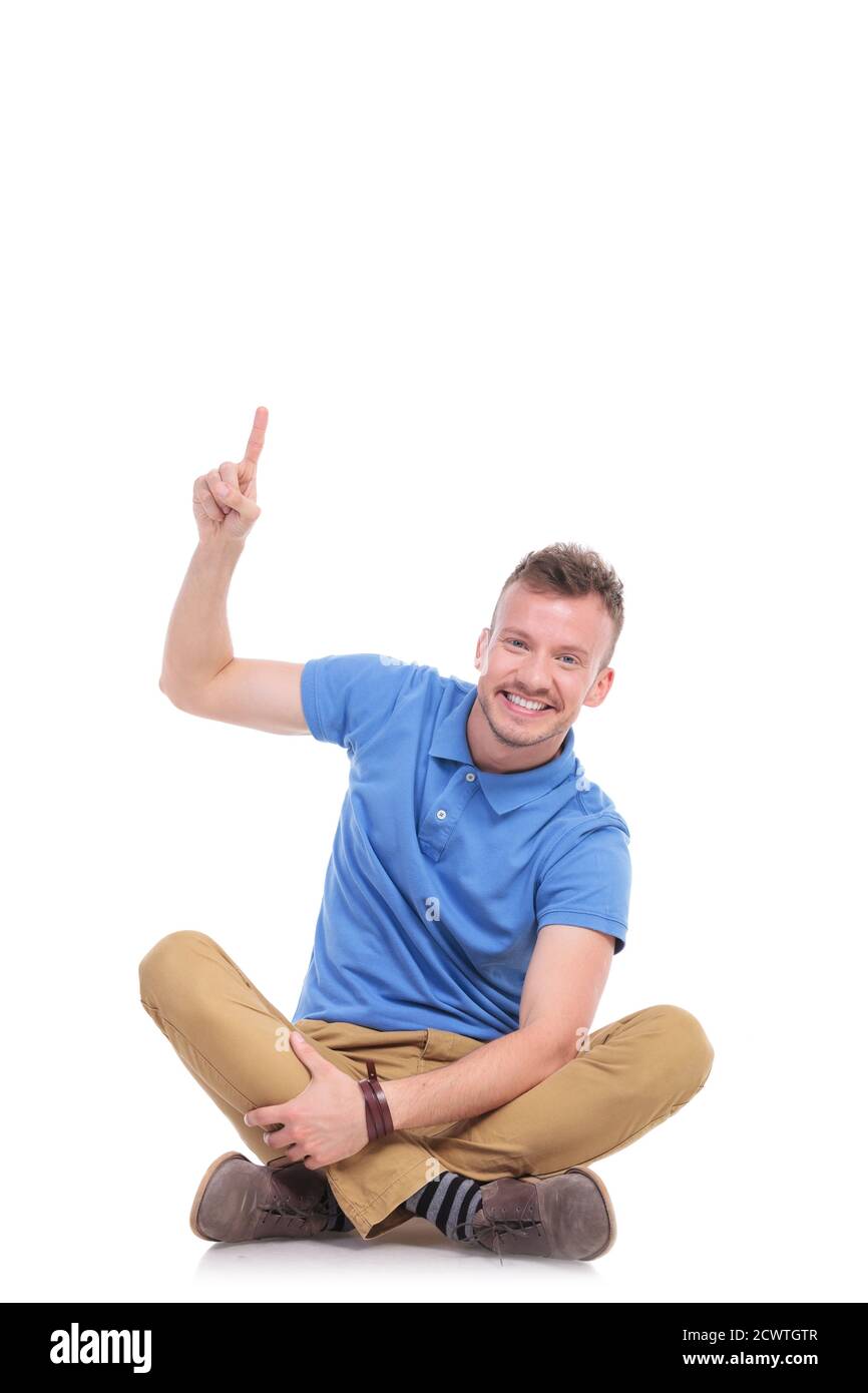 casual young man sitting on the floor with his legs crossed and ...