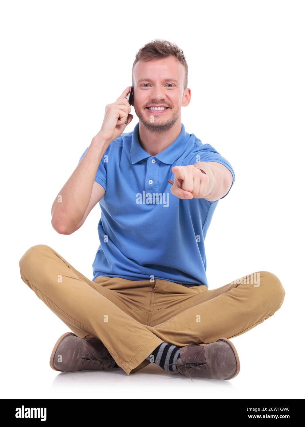 casual young man sitting on the floor with his legs crossed and talking ...