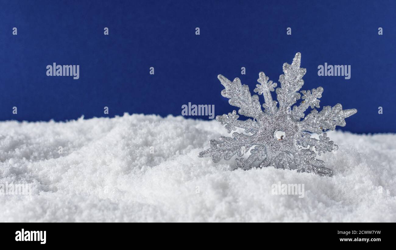 Glass shiny snowflake on snowy background over blue. Christmas and ...