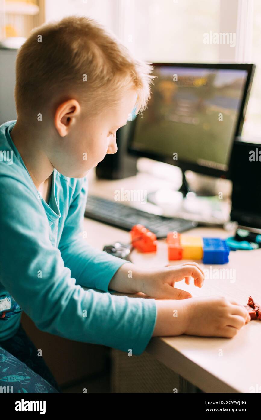 Little Blond Boy Playing In Toys Near Computer Stock Photo - Alamy