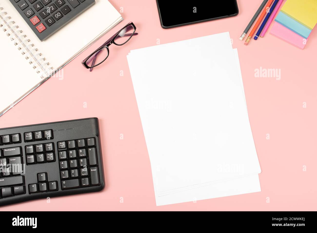 Top view of pink office desk with keyboard, smartphone, glasses and ...