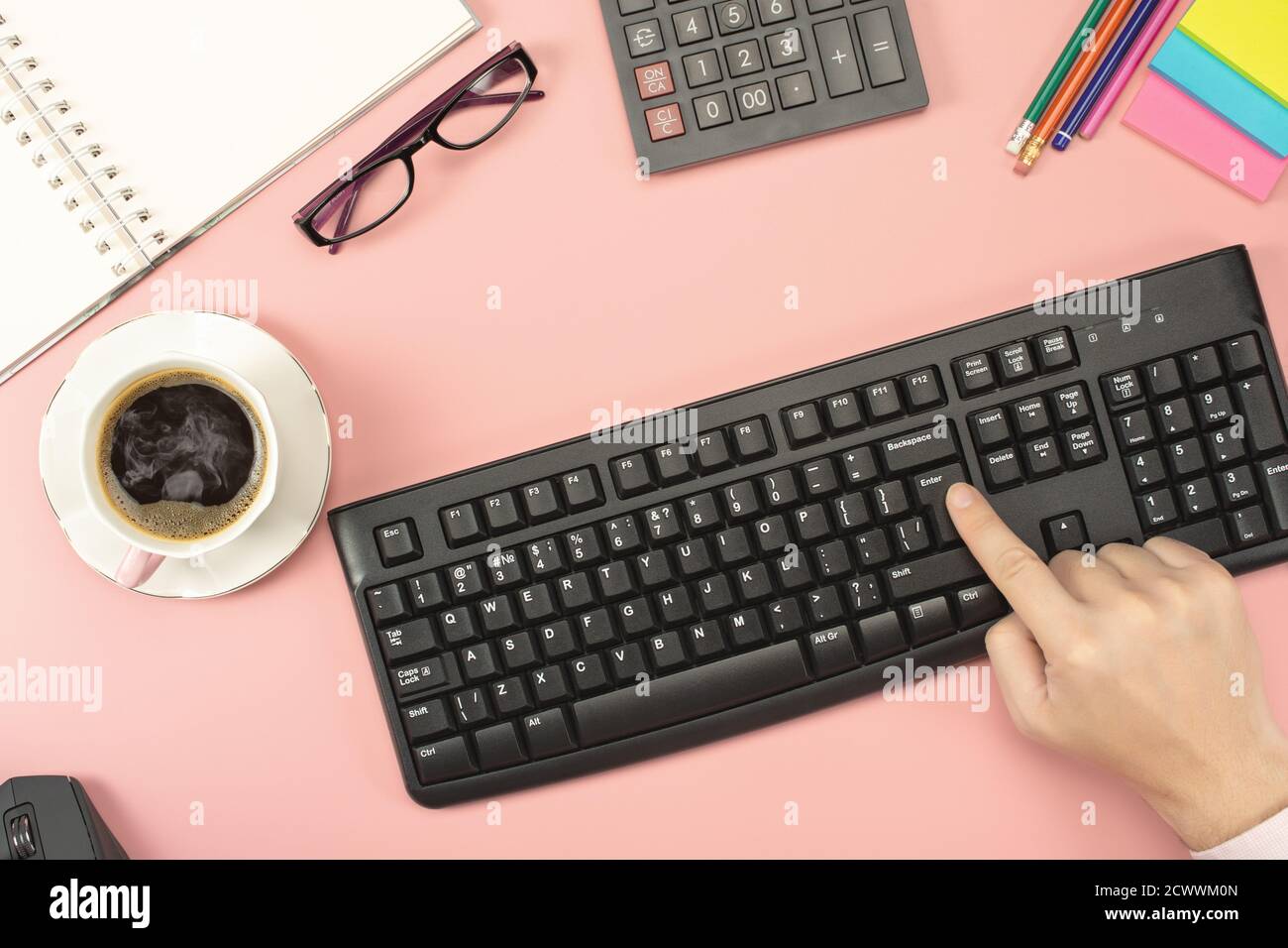 Man sitting at a pink office Desk presses the enter button on the ...