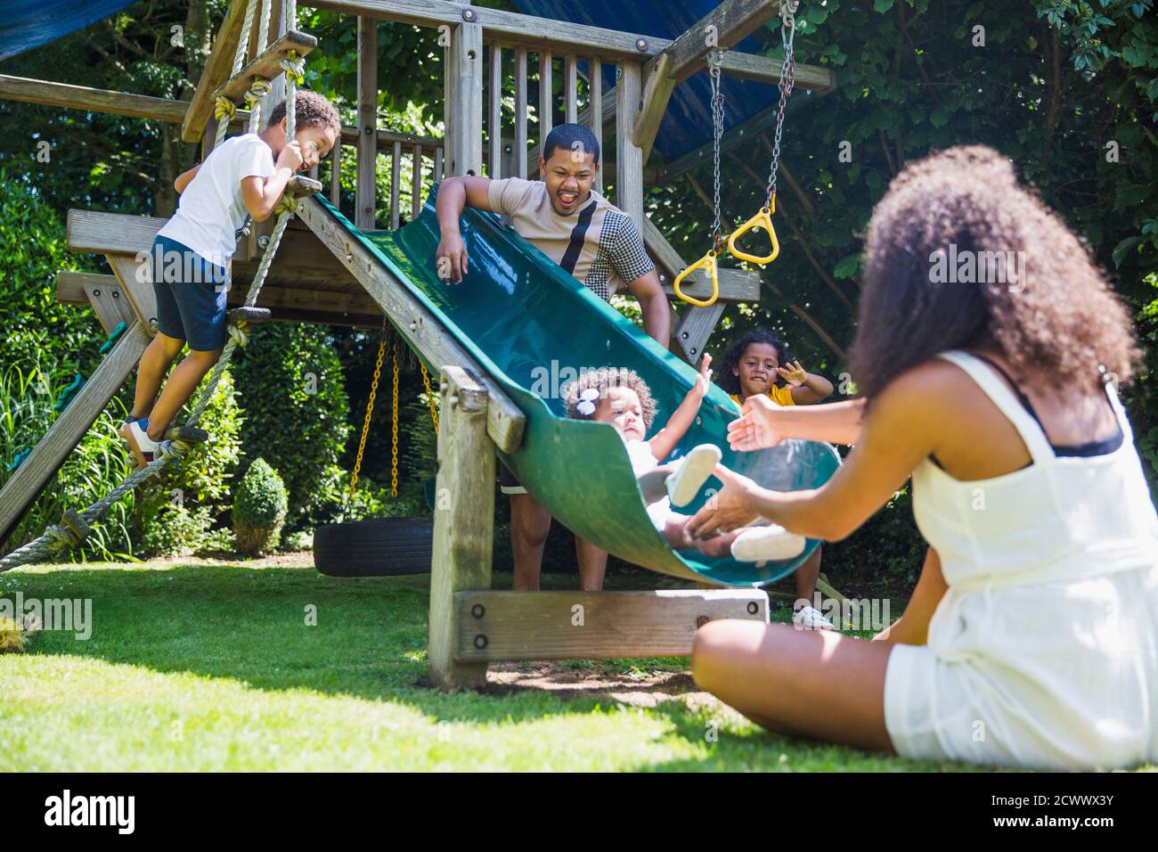 Family playing at play structure in sunny summer backyard Stock Photo ...