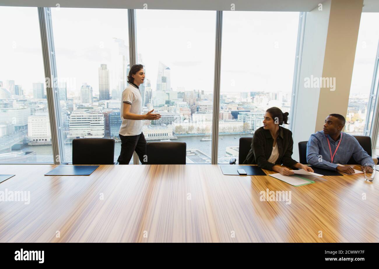 Businessman talking at highrise conference room window, London, UK ...