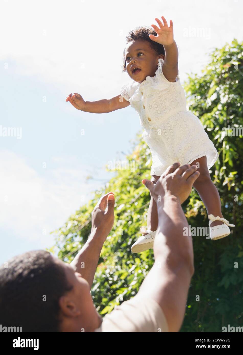Father throwing daughter overhead playfully in sunshine Stock Photo - Alamy