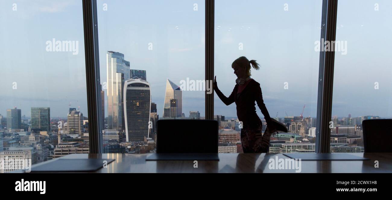 Businesswoman stretching at highrise office window, London, UK Stock ...