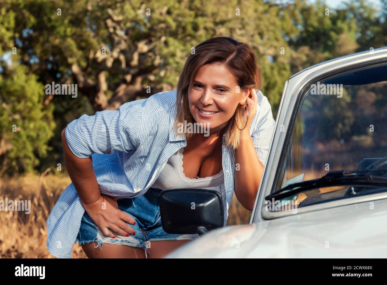 Woman with white convertible vintage car on the countryside, checking ...