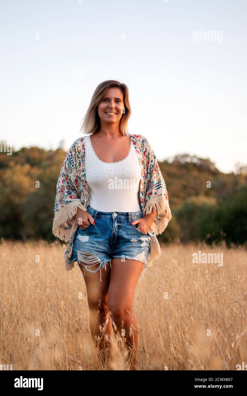 Beautiful girl posing on the countryside with short jeans on the dry ...
