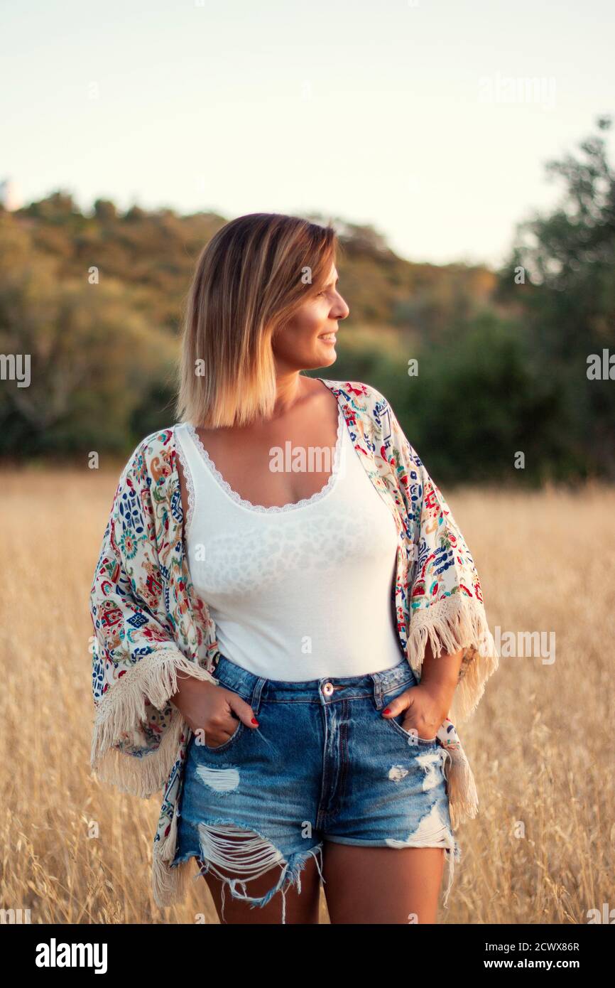 Beautiful girl posing on the countryside with short jeans on the dry ...