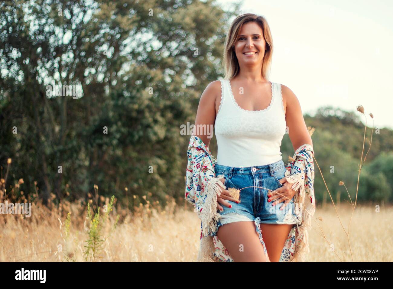 Beautiful girl posing on the countryside with short jeans on the dry ...
