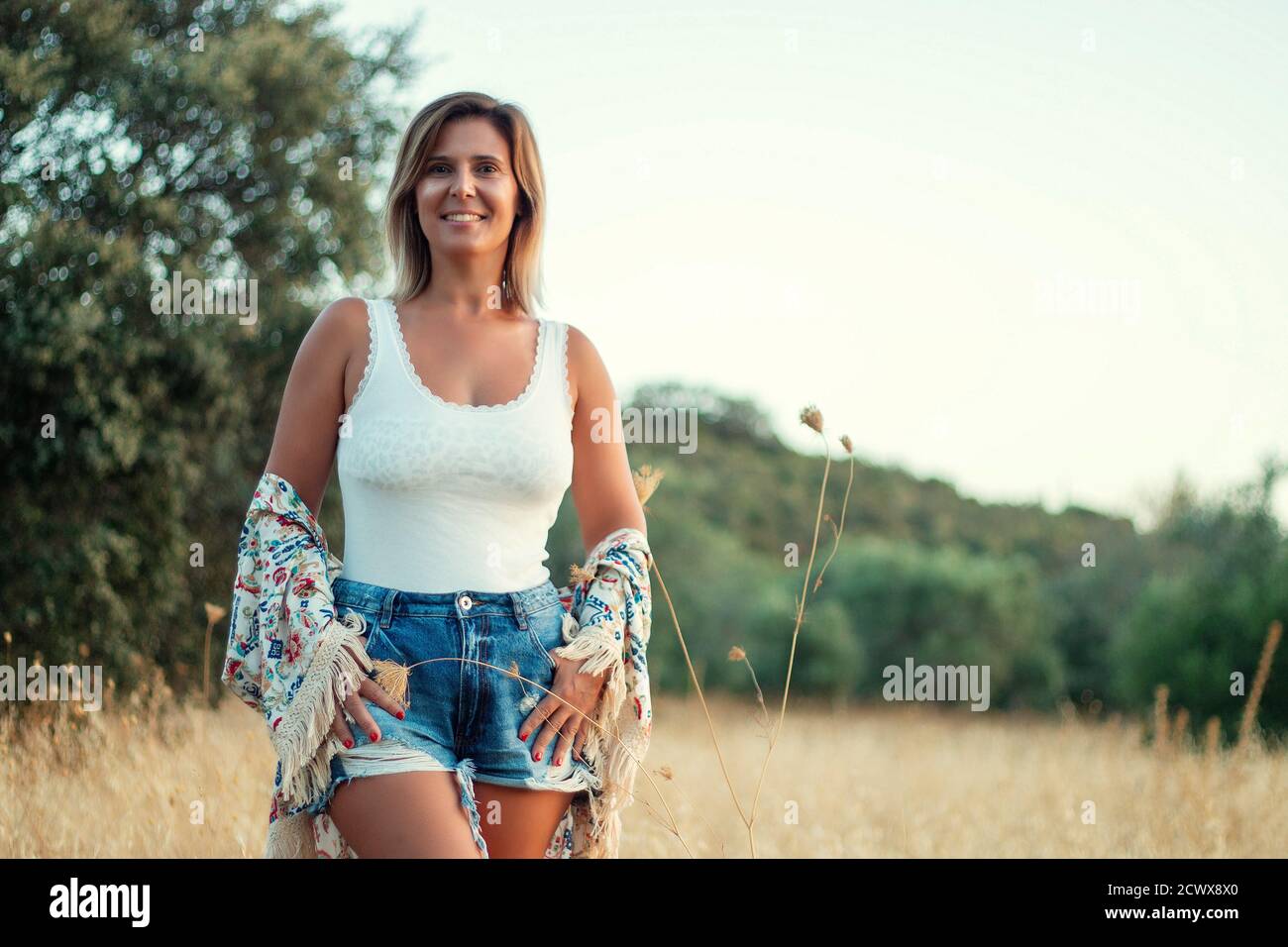 Beautiful girl posing on the countryside with short jeans on the dry ...
