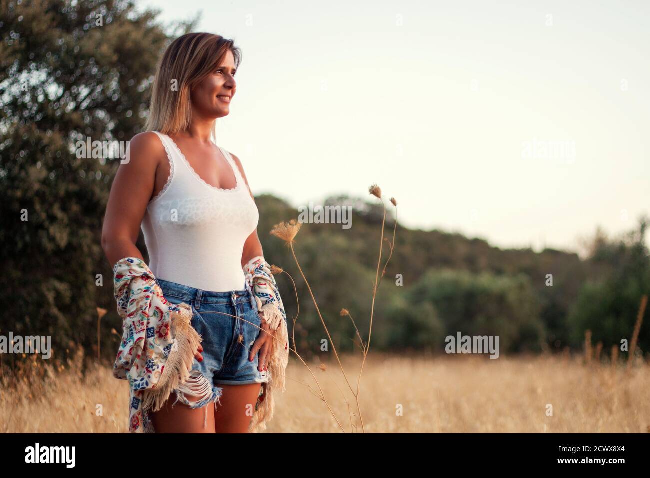 Beautiful girl posing on the countryside with short jeans on the dry ...