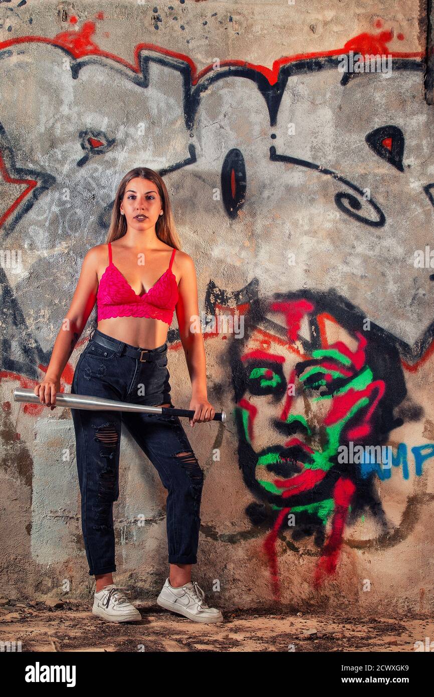 Dangerous girl with bat on a abandoned factory with graffiti on the ...