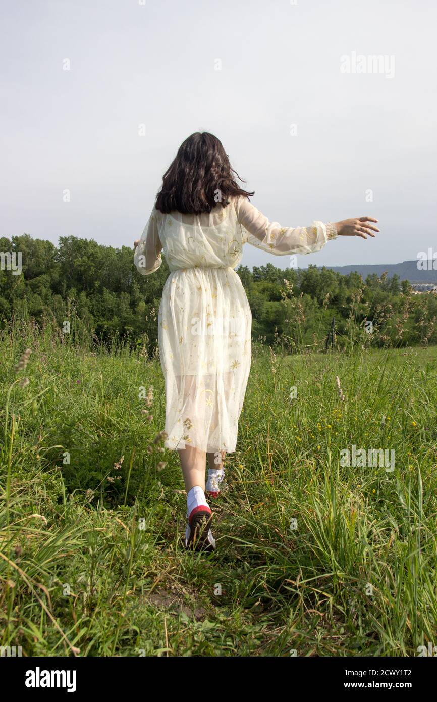 Young woman with her arms wide spread is enjoying in the sunny summer ...