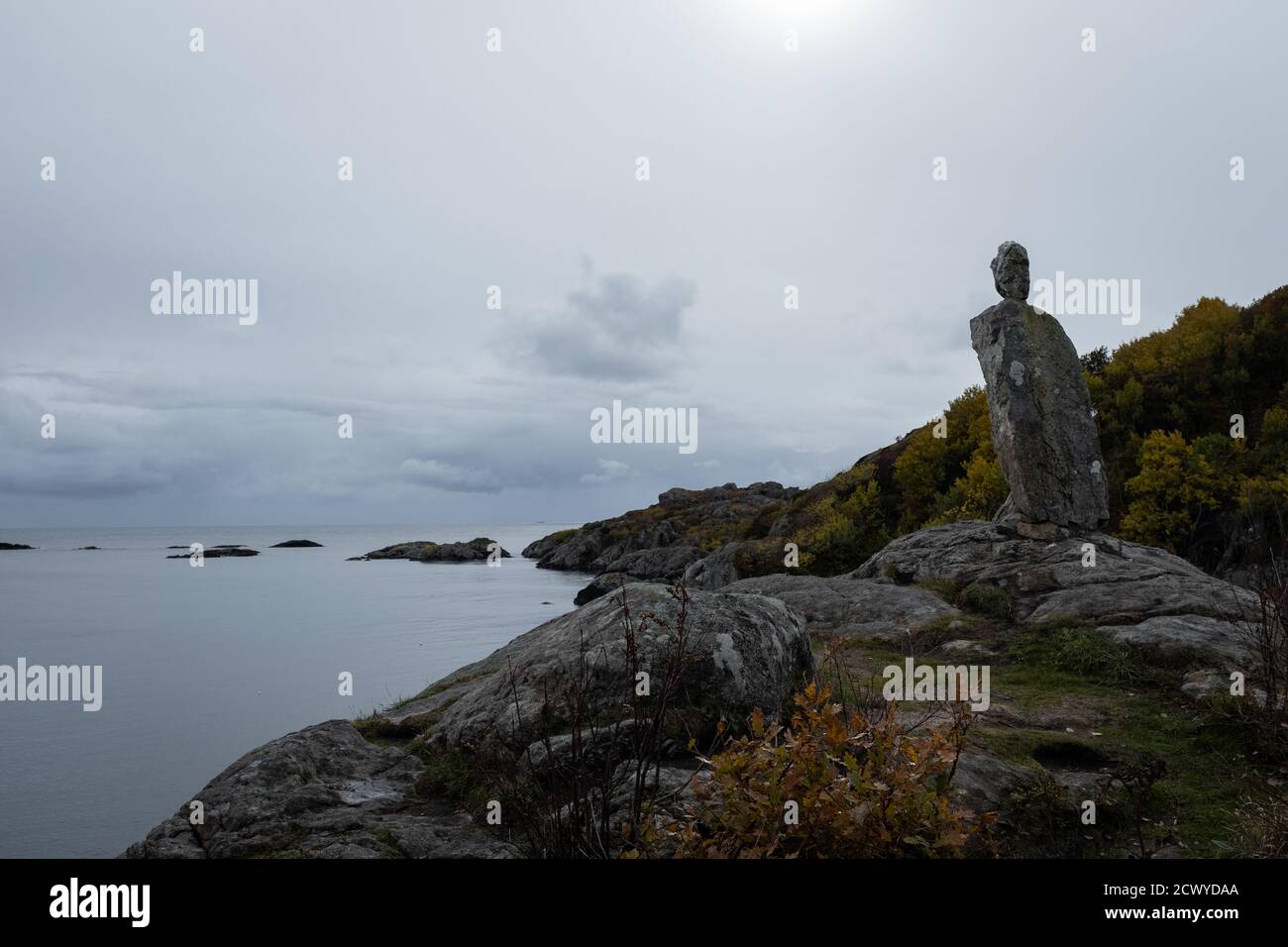 Norwegian fjord landscape with stone statue on shore on overcast day ...
