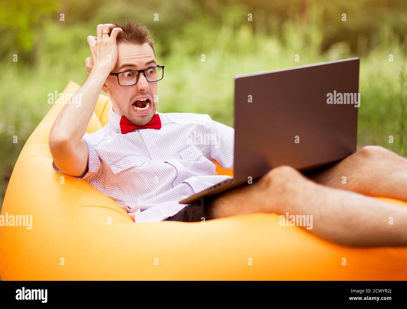 Young freelancer man with shocked face in shirt, red bow tie and ...