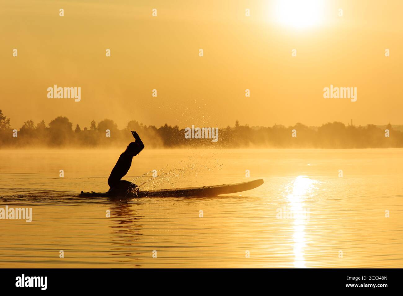 Male surfer splashing water while sitting on paddle board Stock Photo ...