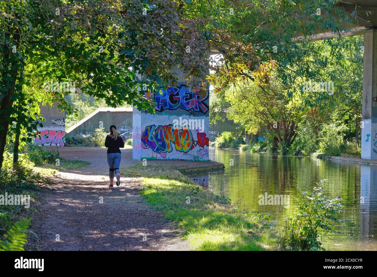 Rear view of a young female runner on the towpath of the Wey navigation ...
