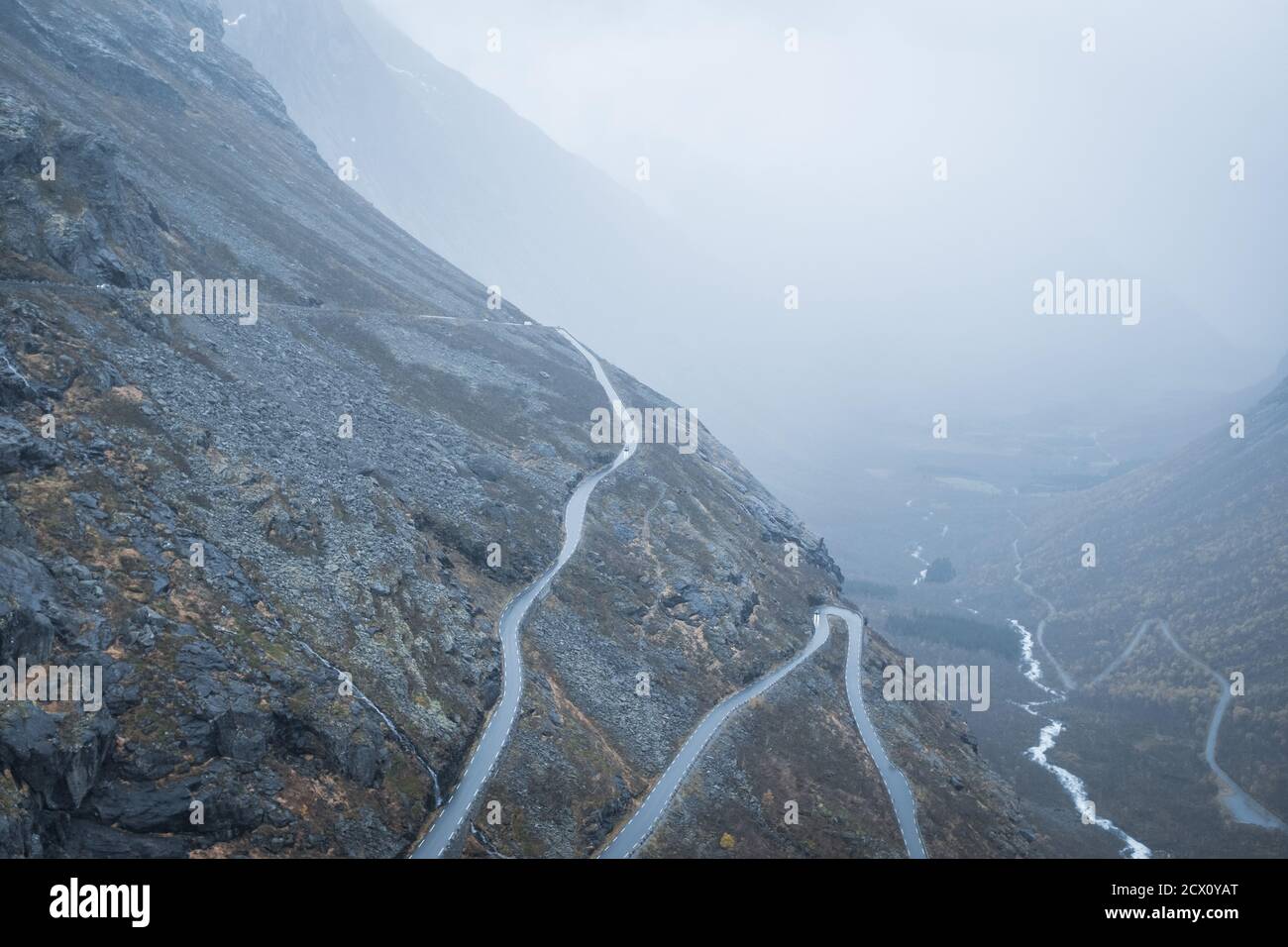 Narrow mountain road on rocky cliffside with mist in background. Norway ...