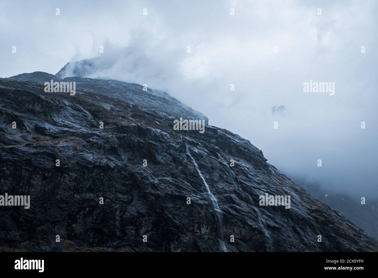 Mountain cliff with cloud covering rocky top Stock Photo - Alamy