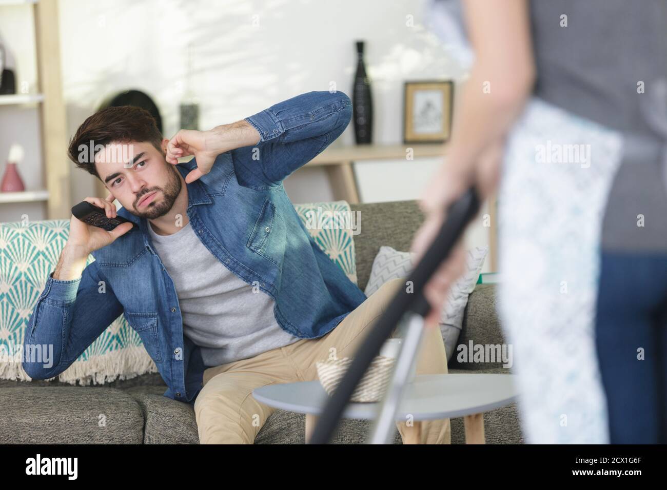 man covering ears while woman is hoovering Stock Photo - Alamy