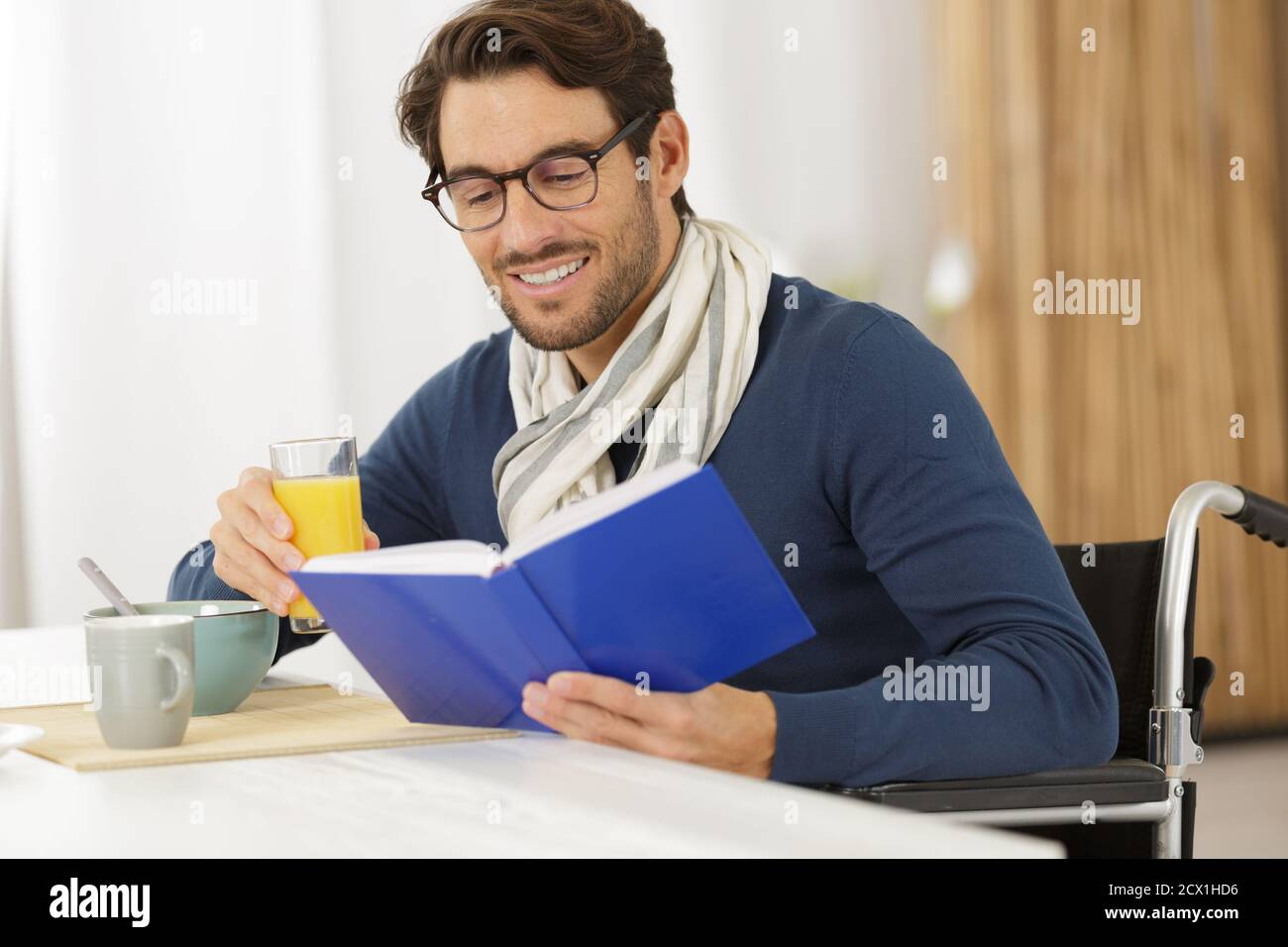 disabled young man reading book while having breakfast Stock Photo - Alamy
